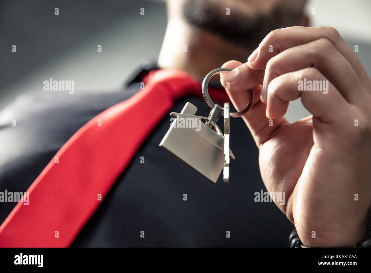 House-shaped keychain with key holded by an elegant man with red tie ...