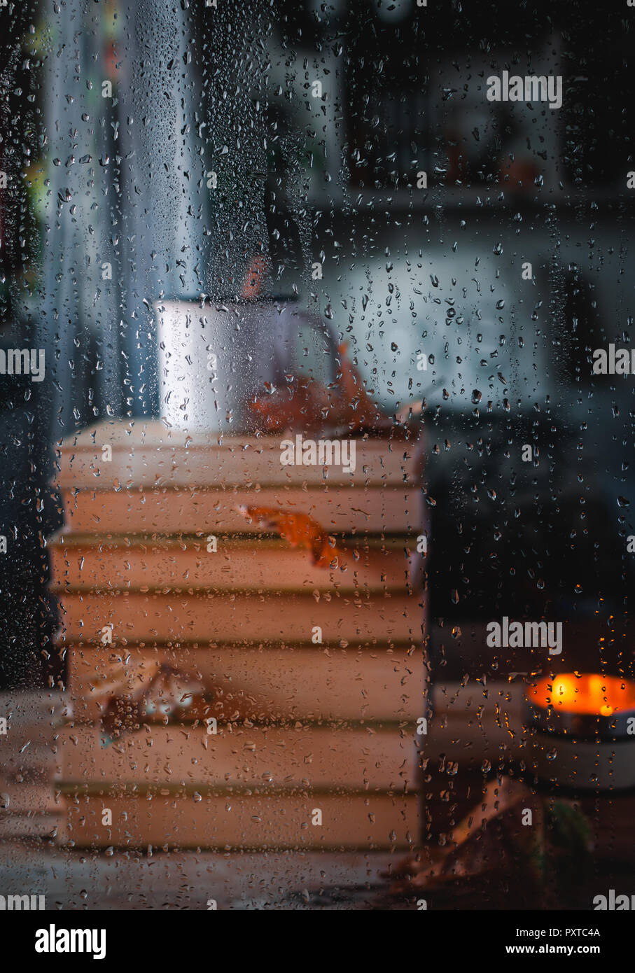 Stacked books and hot tea through rainy window Stock Photo - Alamy