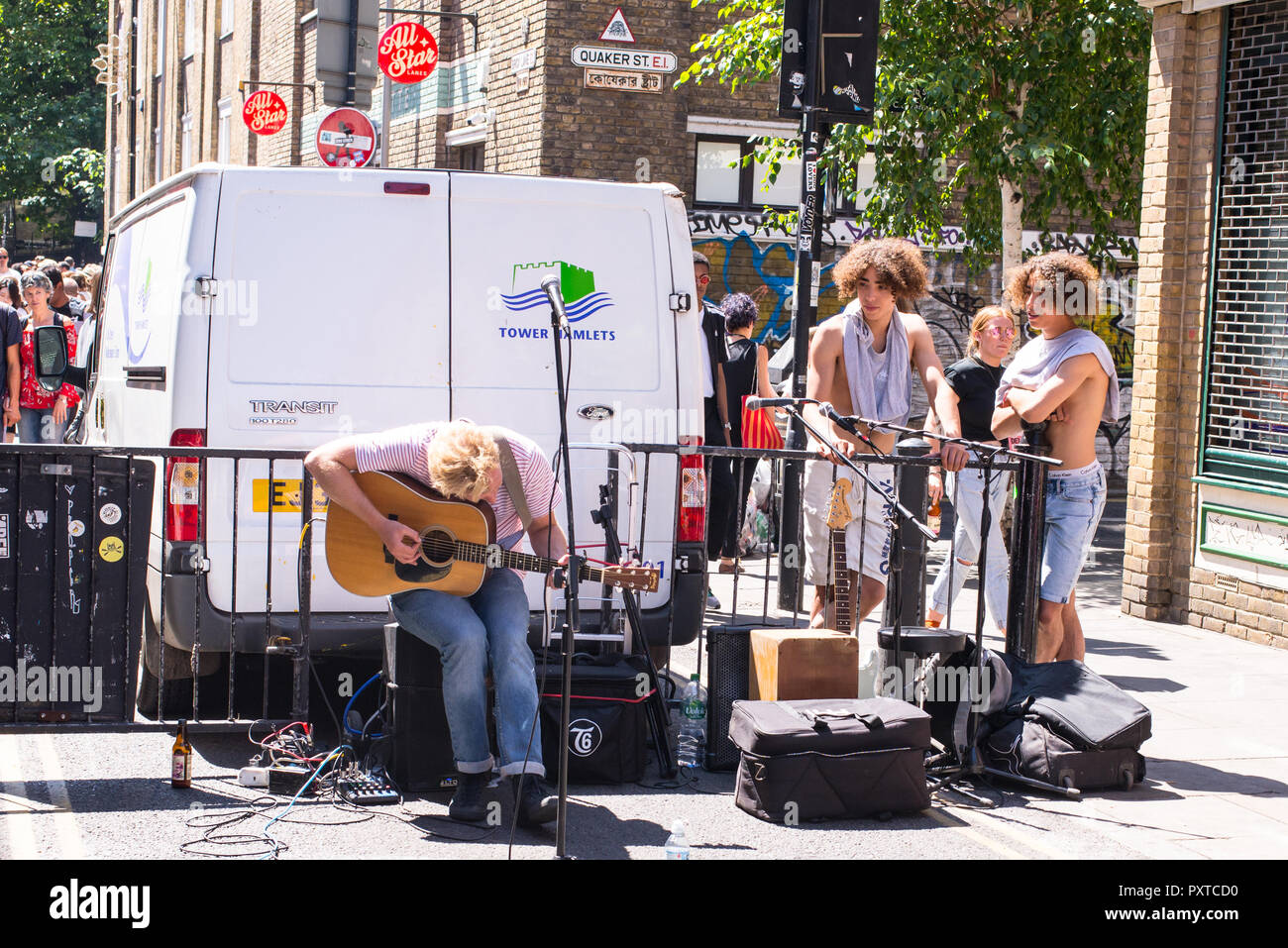 Two identycal boys twins watching a busker guitarist musician playing ...