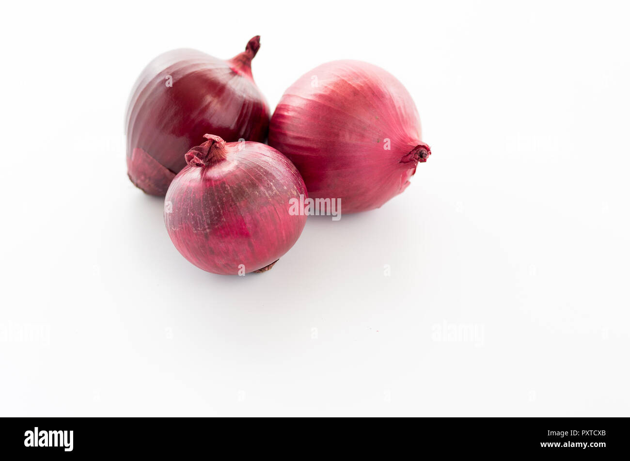 Three heads of red onions. A pile of onions on a white background ...