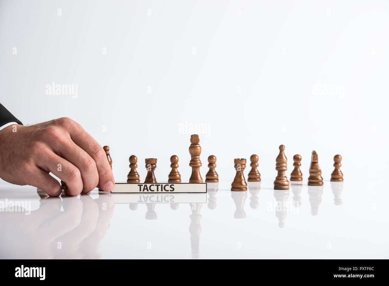 Business leader holding a tactics sign in front of wooden chess pieces ...