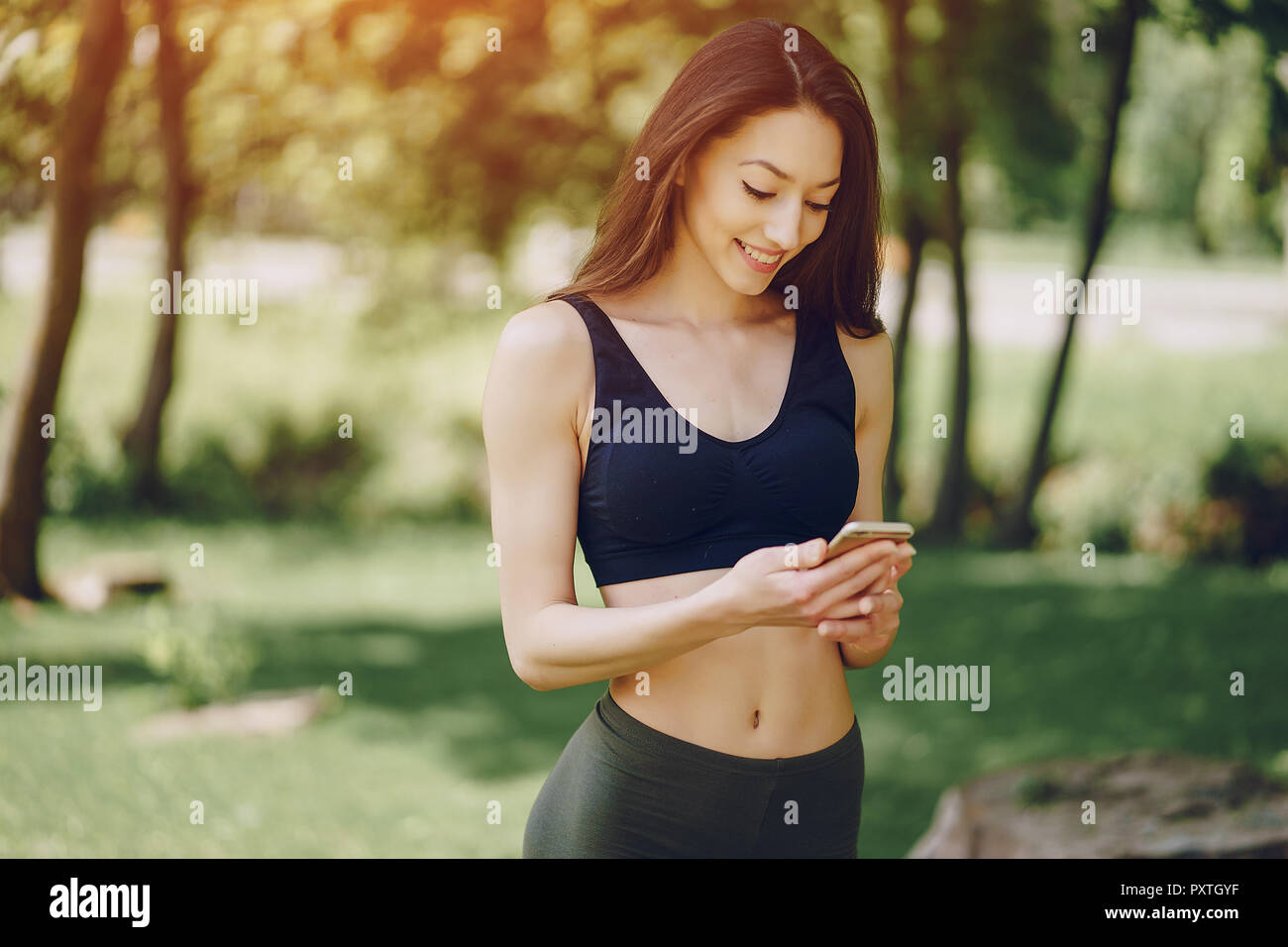 A young and beautiful girl in black toe uses a phone in the nature ...