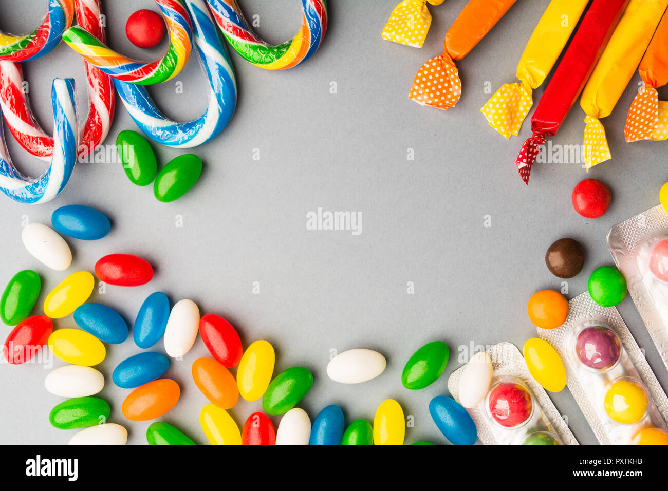 Five types of colorful candies over grey background, top view with copy ...