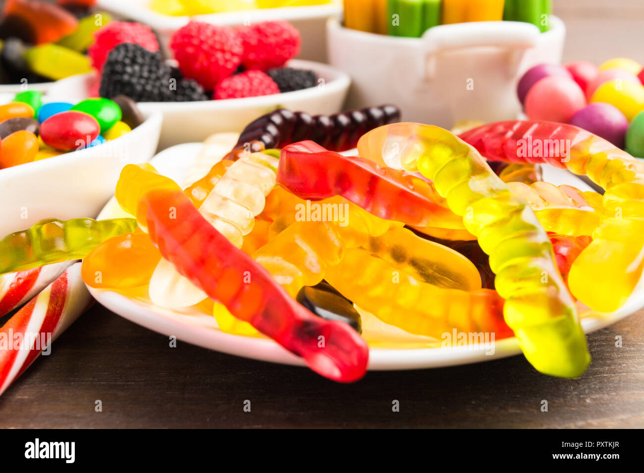 Jelly sweet worms on plate over brown wooden background, closeup view ...