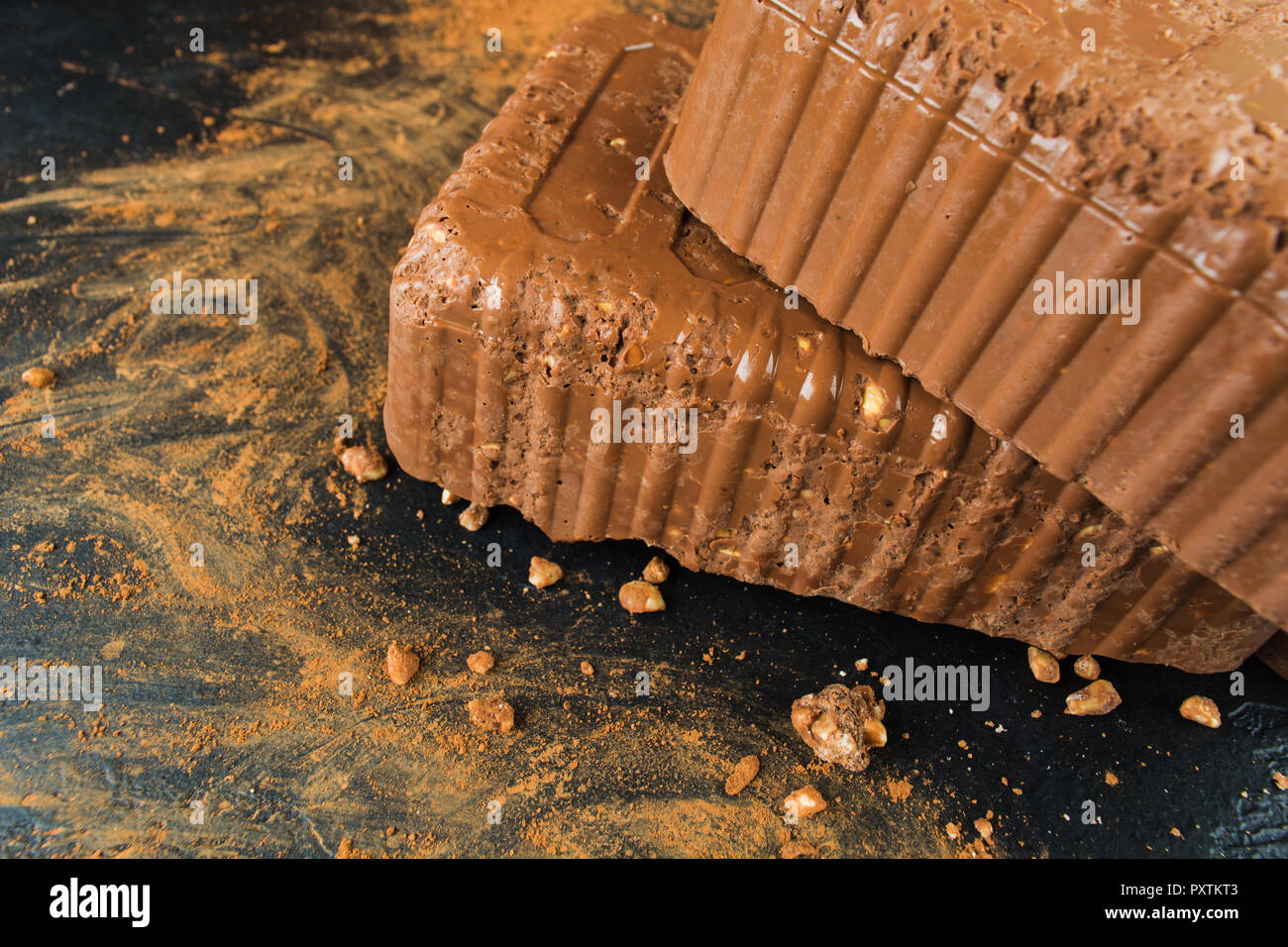 Milk chocolate in big blocks with cacao around over black background ...