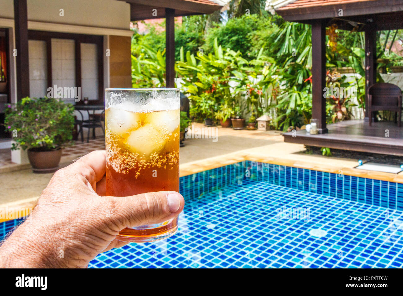 Hand holding a rum and coke cocktail in glass with ice Stock Photo - Alamy