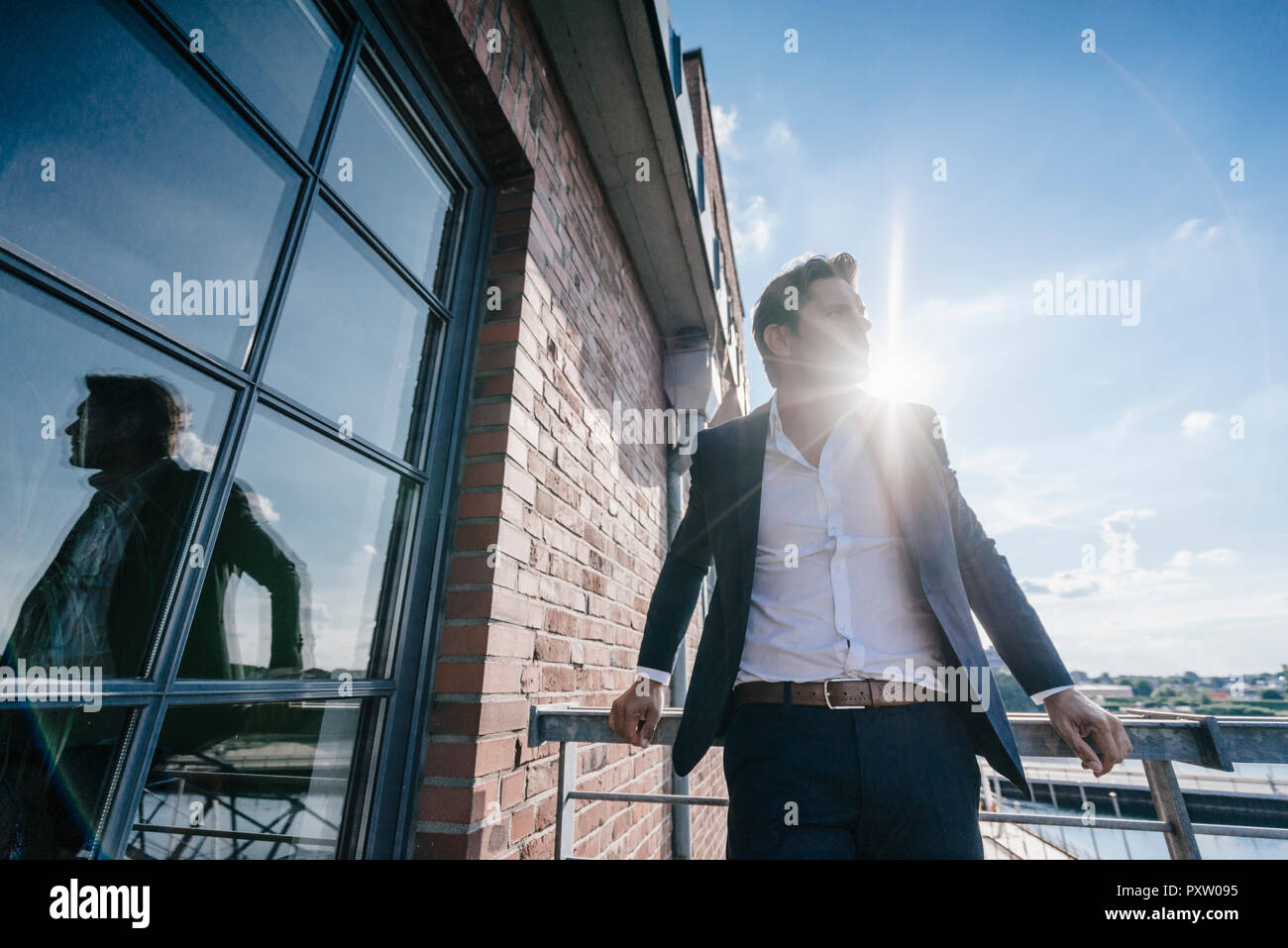 Successful businessman standing on balcony Stock Photo - Alamy