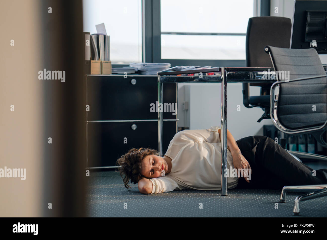 Tired businesswoman sleeping on floor under her desk Stock Photo - Alamy