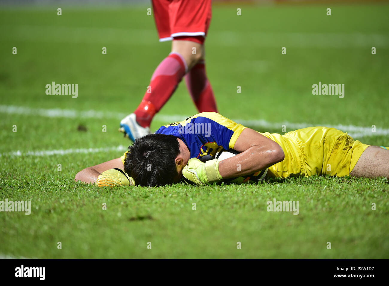The goalkeeper lies on the ground clutching the ball Stock Photo - Alamy