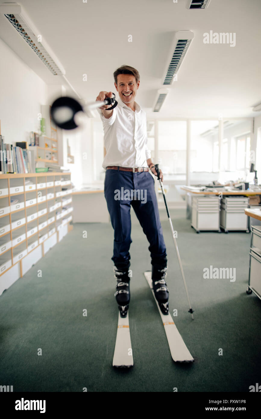 Businessman skiing in office, pointing with ski pole Stock Photo - Alamy
