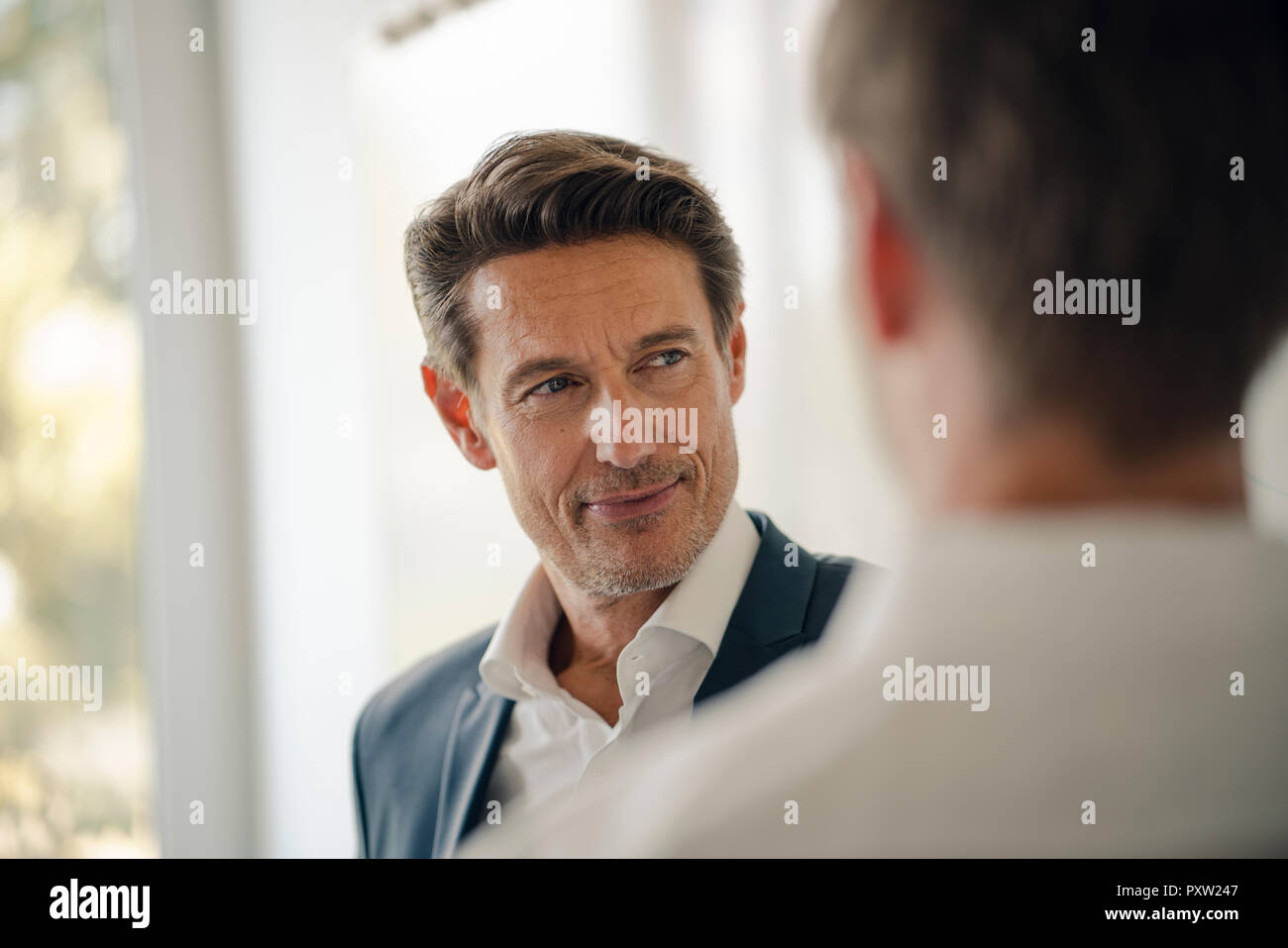 Mature businessman talking to colleague at a meeting Stock Photo - Alamy