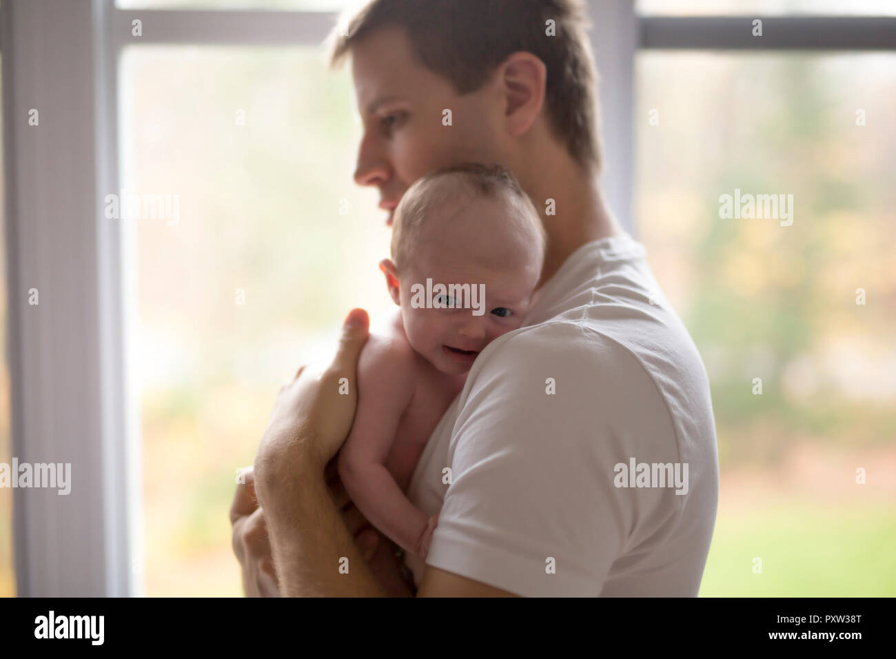 happy family father with newborn baby in front of window Stock Photo ...