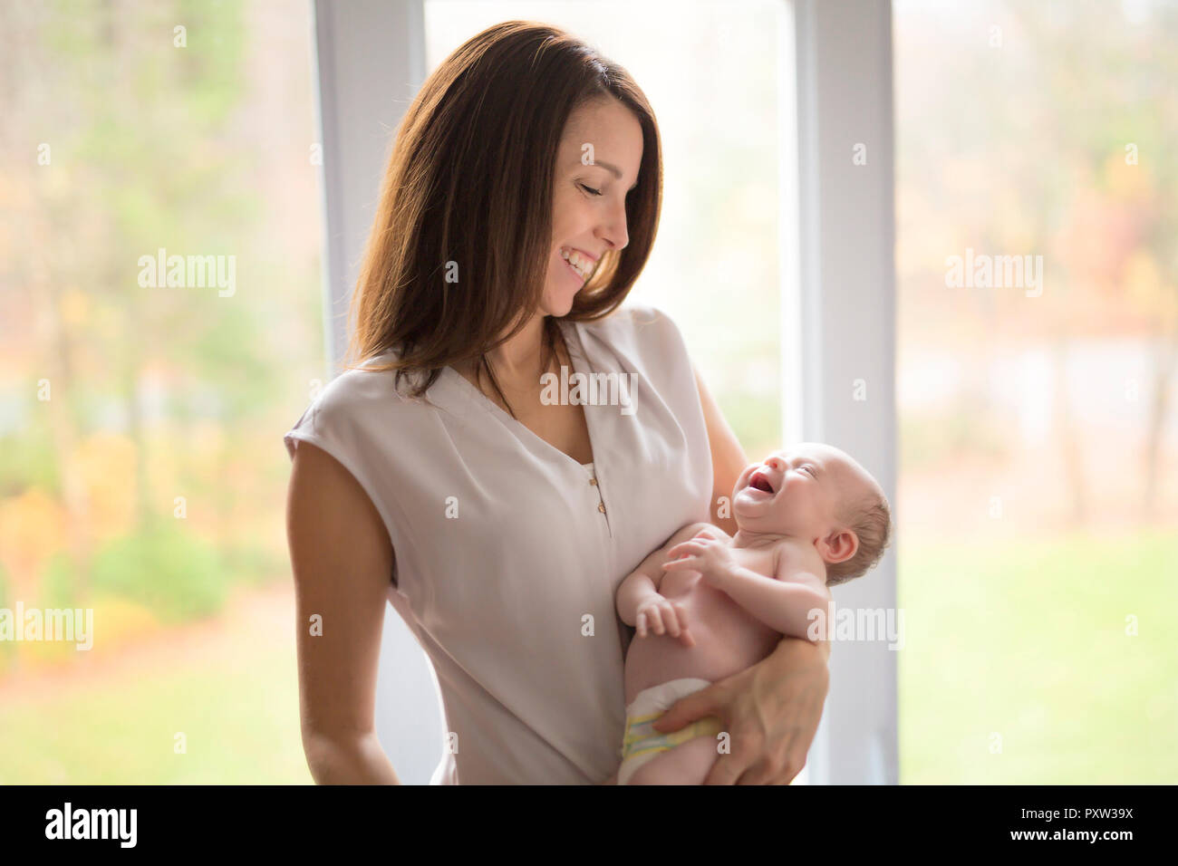happy family mother with newborn baby in front of window Stock Photo ...