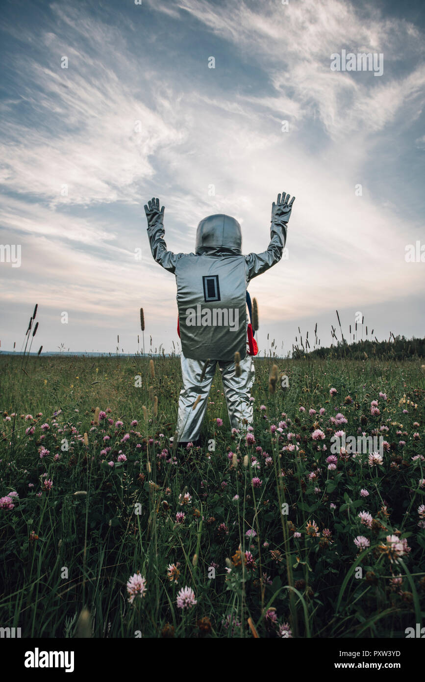 Spaceman exploring nature, standing in meadow, waving Stock Photo - Alamy