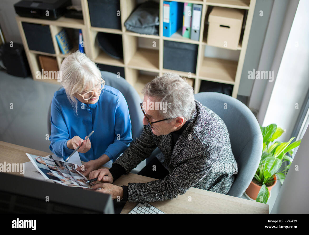 Two senior colleagues working together desk office discussing photos hi ...