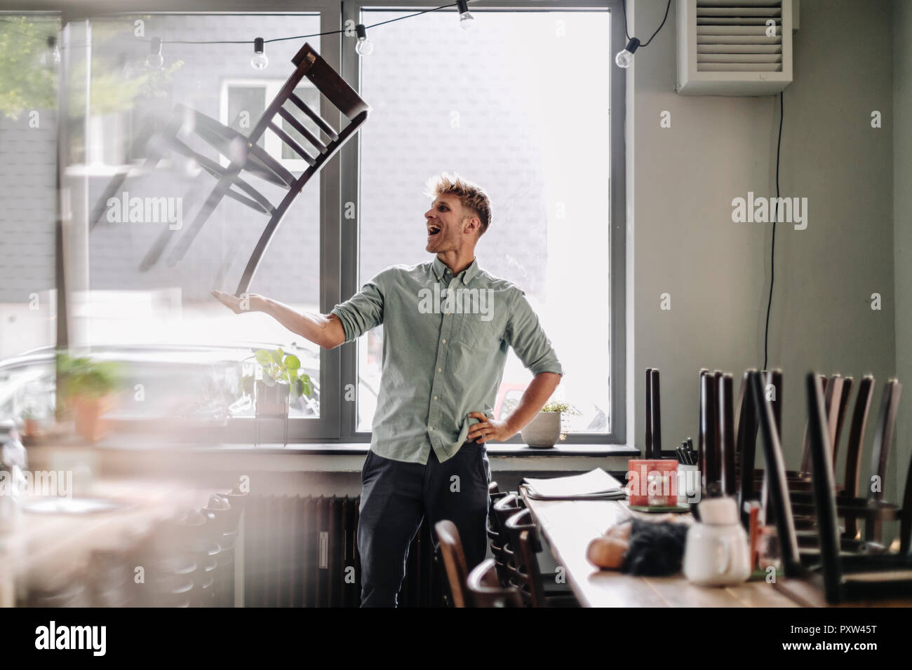 Man balancing chair on his hand, closing his coffee shop Stock Photo ...