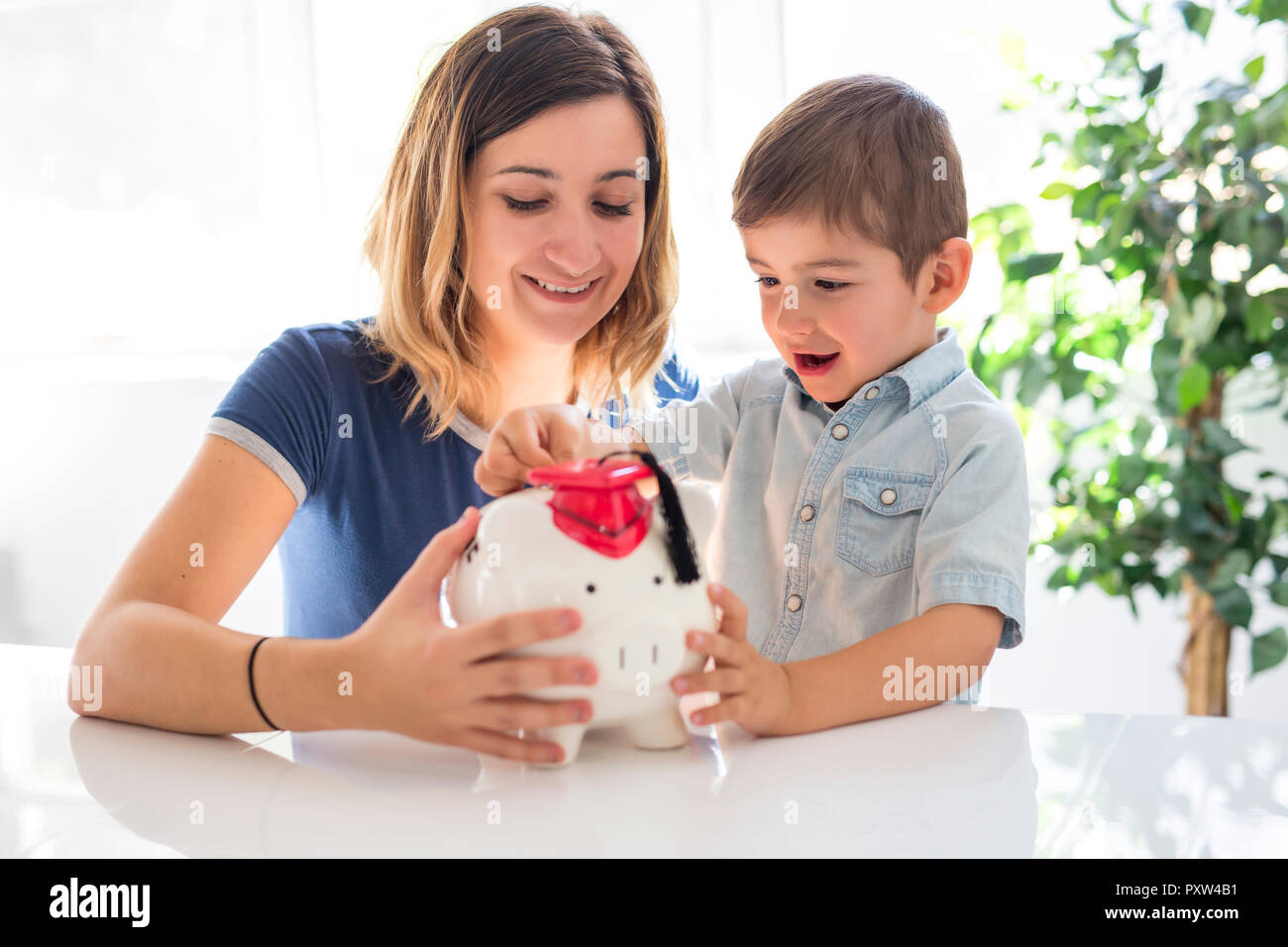 A Little boy and his mother inserting money into piggy bank. Mother ...