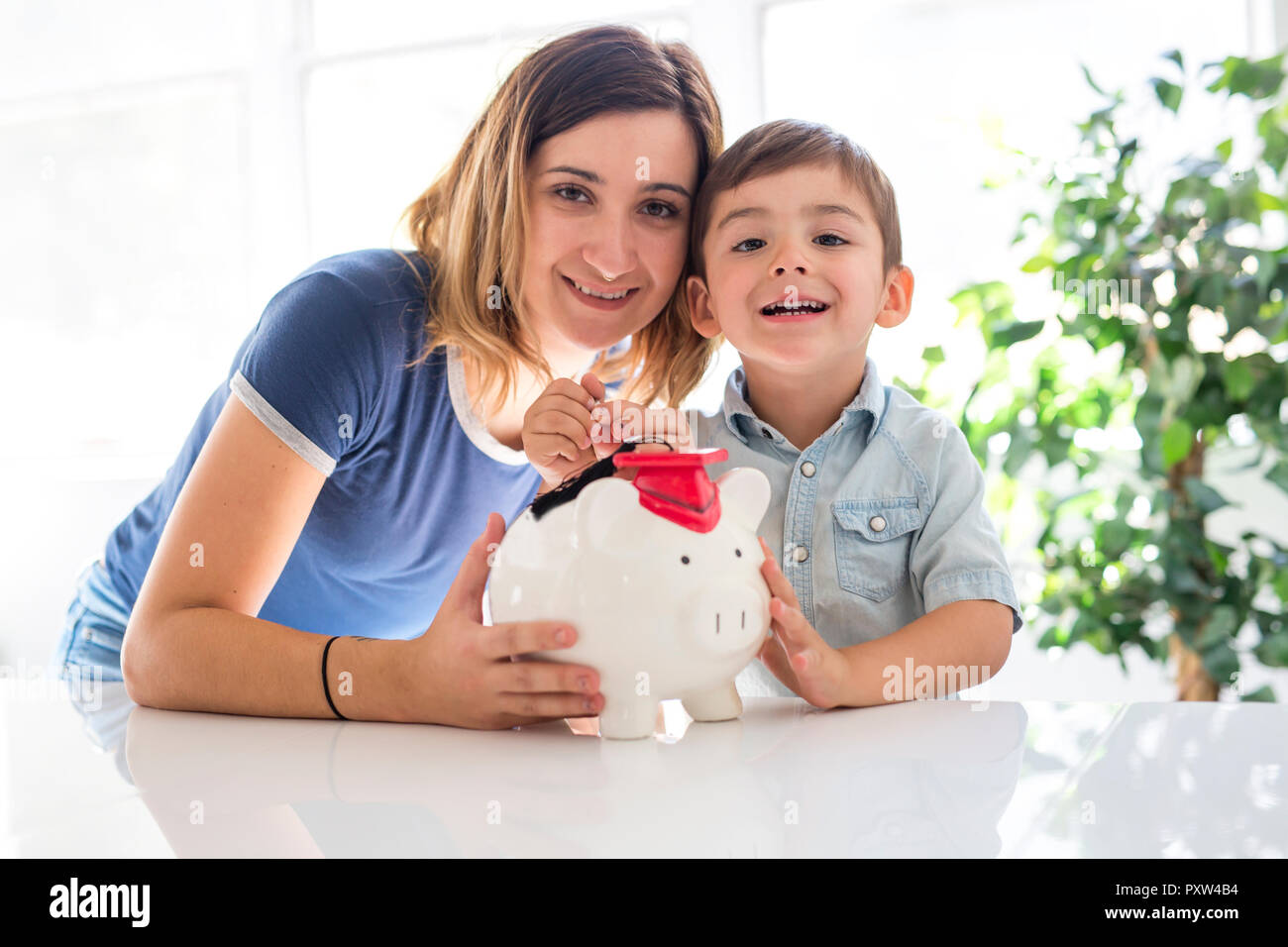 A Little boy and his mother inserting money into piggy bank. Mother ...
