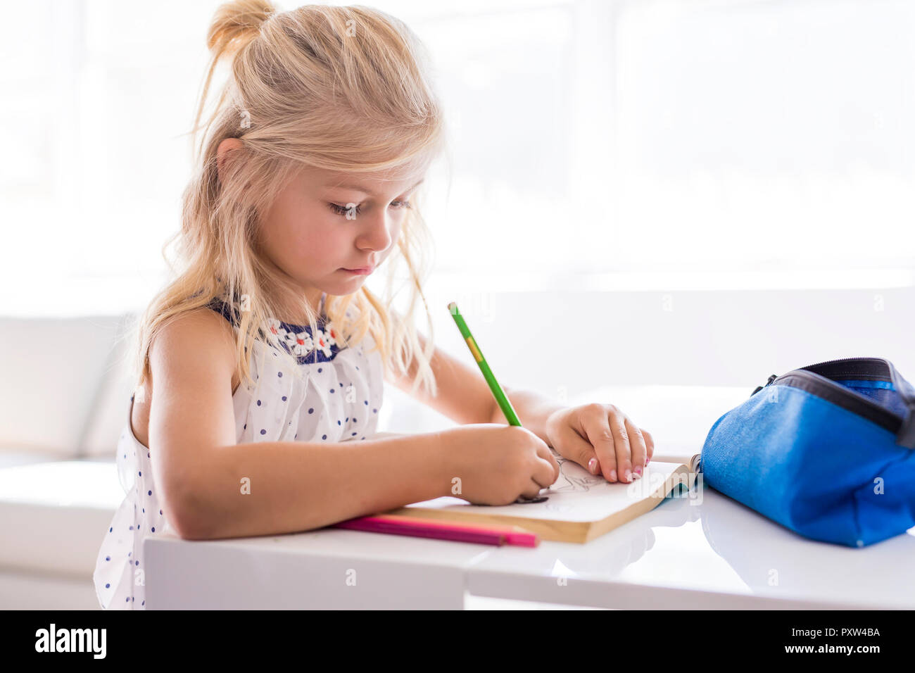 A little girl drawing in the kitchen table Stock Photo - Alamy