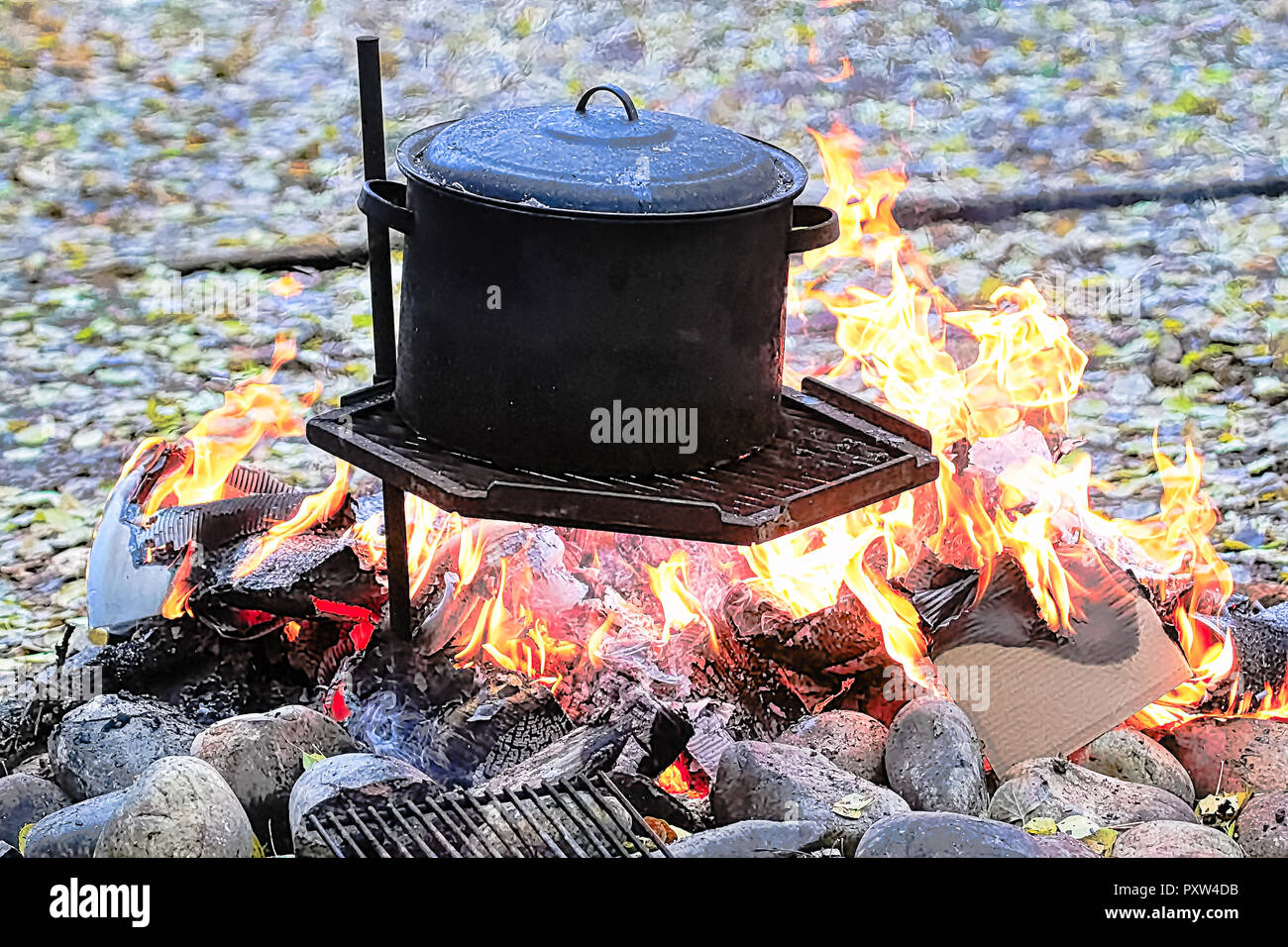 A black pot on a grill over a large fire Stock Photo - Alamy