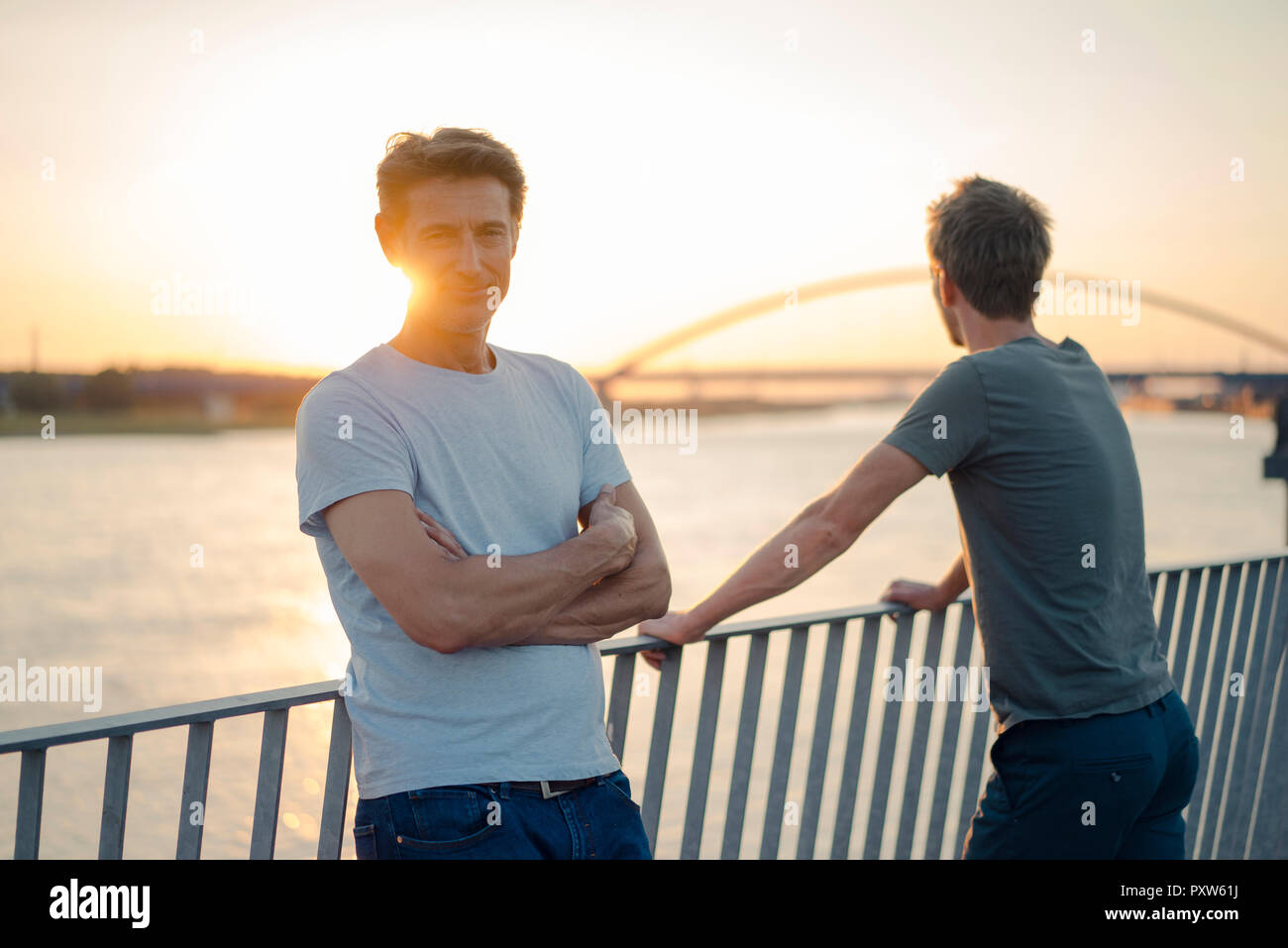 Two friends watching sunset at the river Stock Photo - Alamy