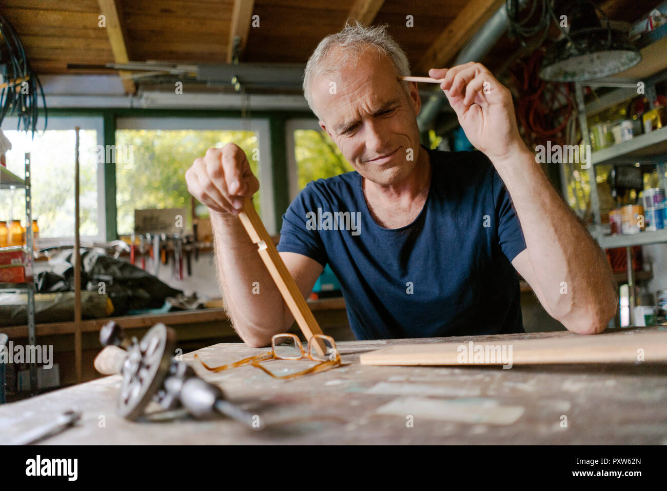 Mature man at workbench in his workshop thinking Stock Photo - Alamy
