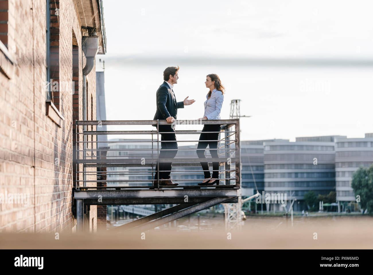 Business people standing on balcony, discussing Stock Photo - Alamy