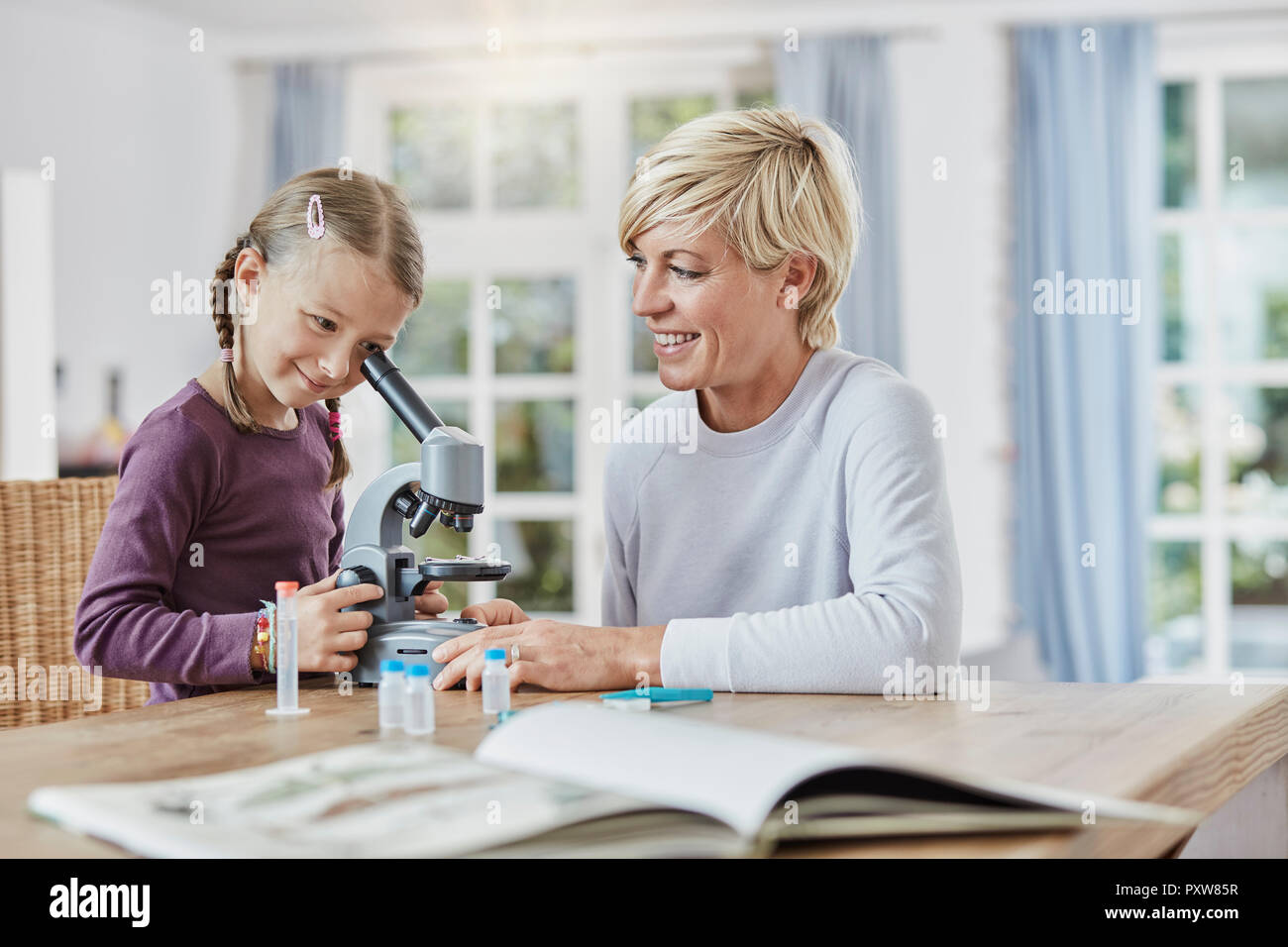 Mother and daughter using microscope at home Stock Photo - Alamy