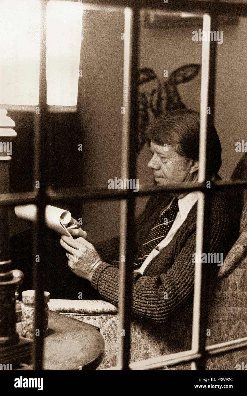 President Jimmy Carter dons his cardigan sweater and makes notes before ...