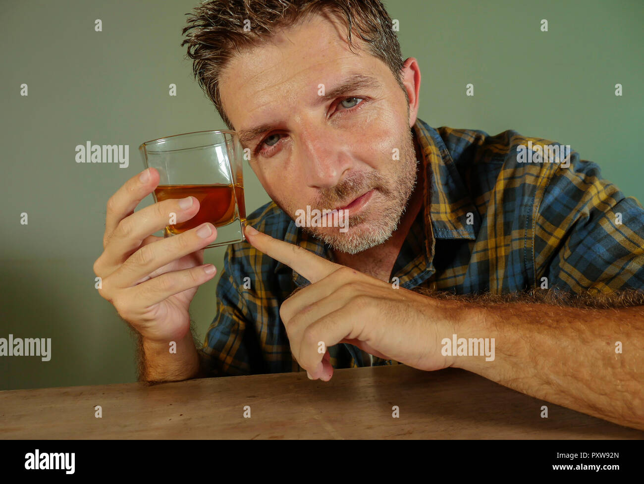 young drunk addict and alcoholic man drinking whiskey glass intoxicated and wasted smiling ...