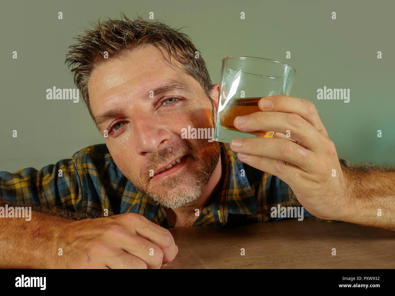young drunk addict and alcoholic man drinking whiskey glass intoxicated and wasted smiling ...