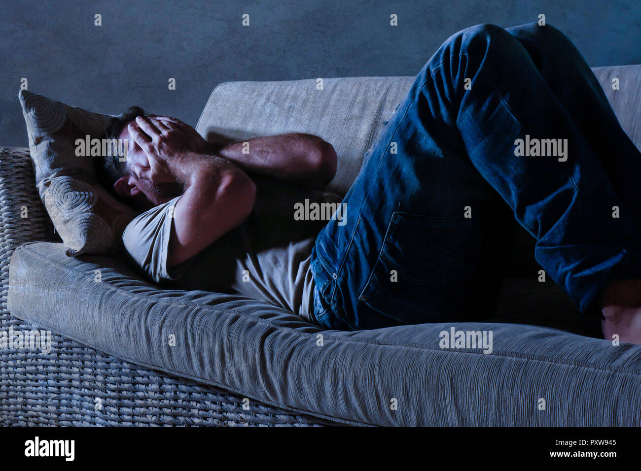 lifestyle dramatic light portrait of young sad and depressed man lying ...