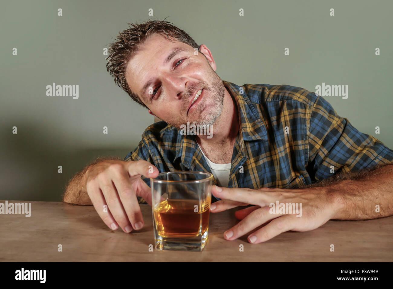 young drunk and pissed alcoholic man wasted drinking whiskey glass intoxicated and messy ...