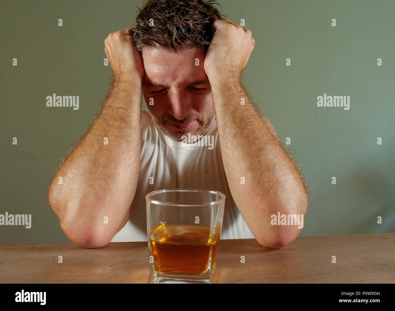 young wasted and depressed alcohol addict man in singlet drinking glass ...