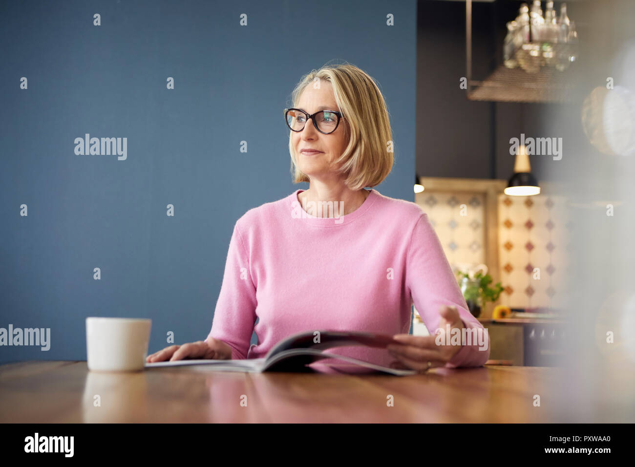 Smiling mature woman reading magazine at home Stock Photo - Alamy