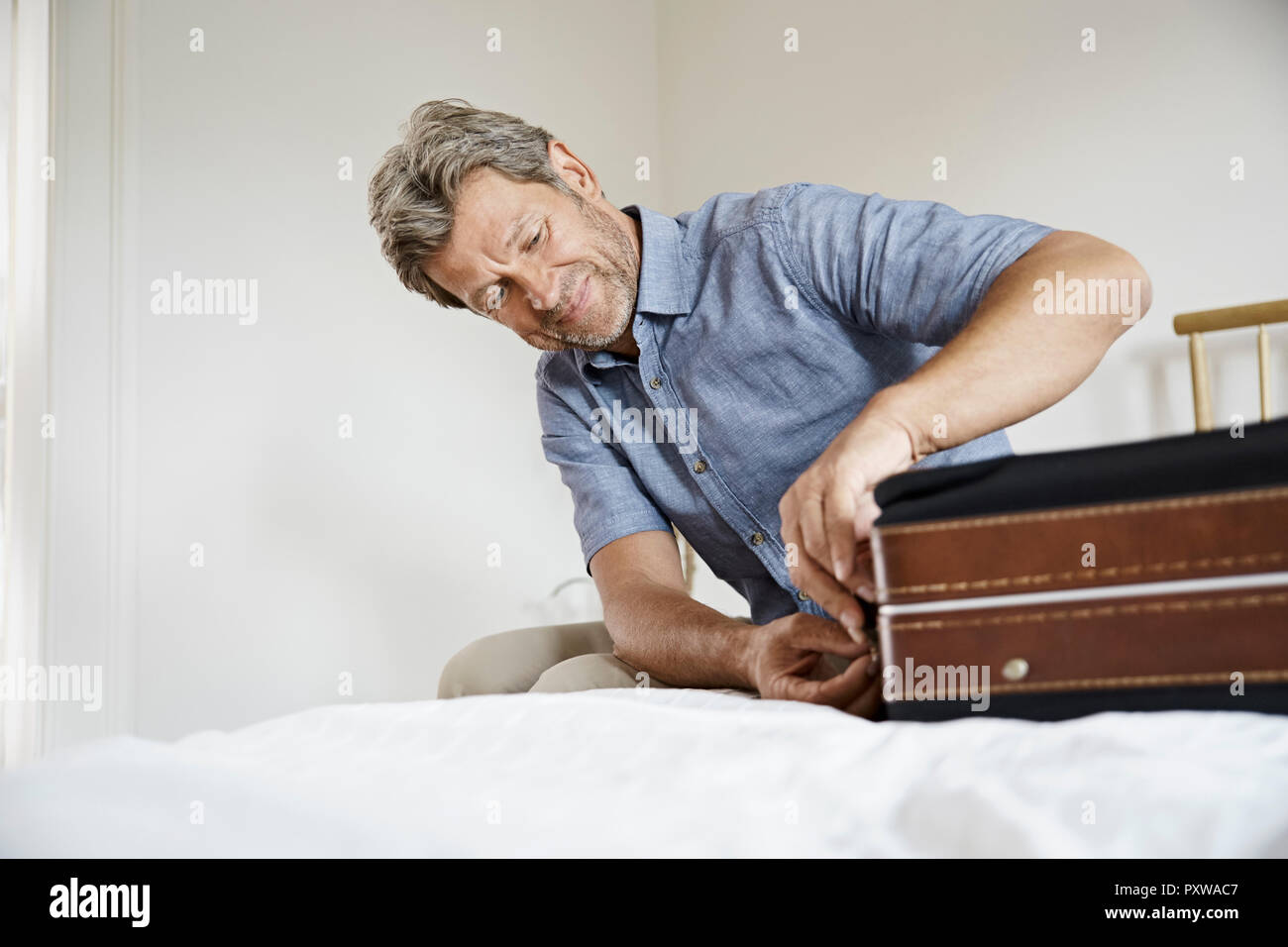 Mature man packing suitcase in bedroom Stock Photo - Alamy