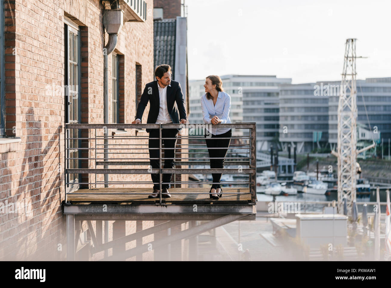 Business people standing on balcony, discussing Stock Photo - Alamy