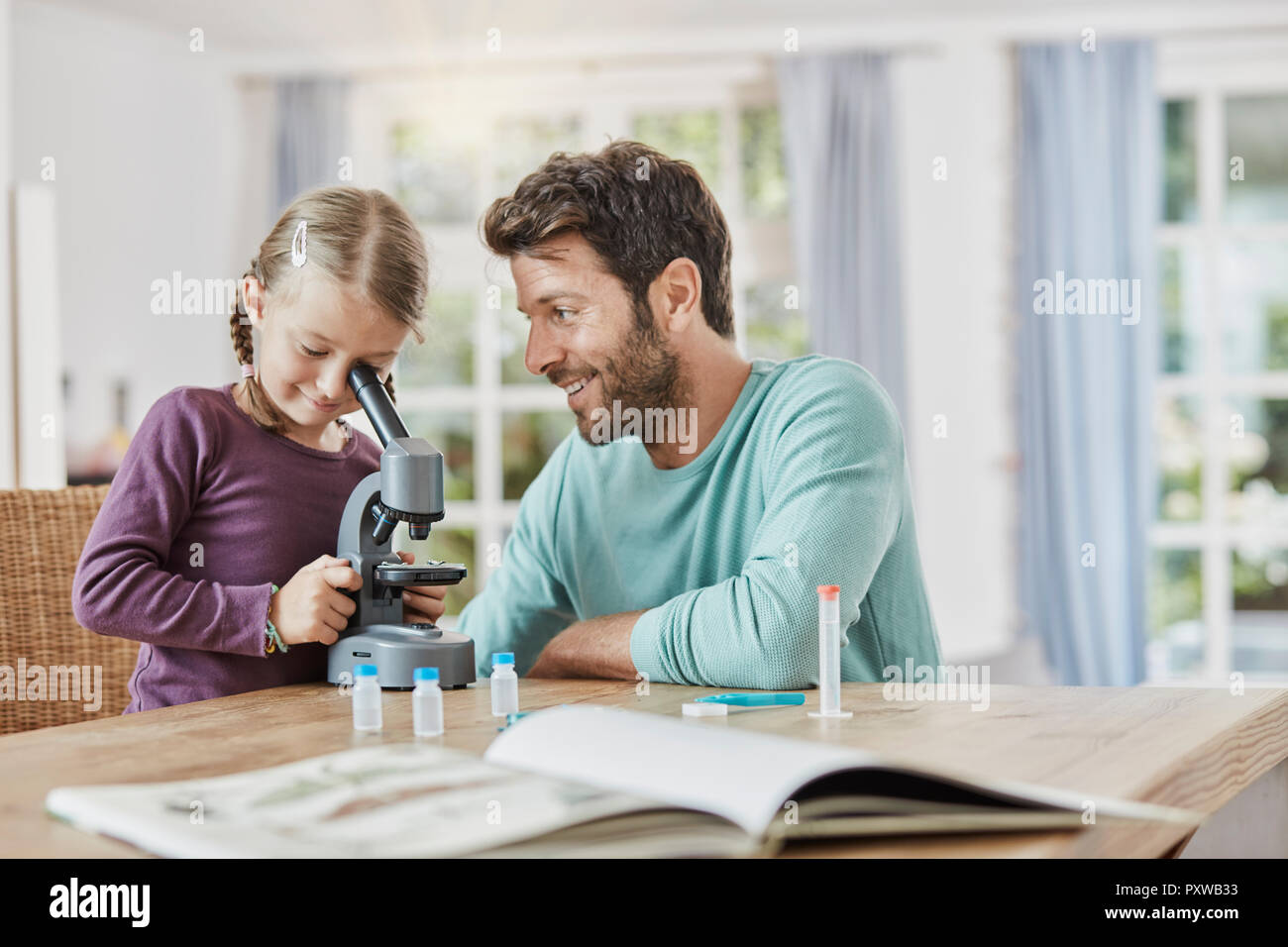 Father and daughter using microscope at home Stock Photo - Alamy