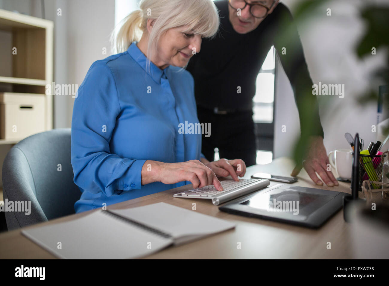 Two senior colleagues working together at desk in office Stock Photo ...