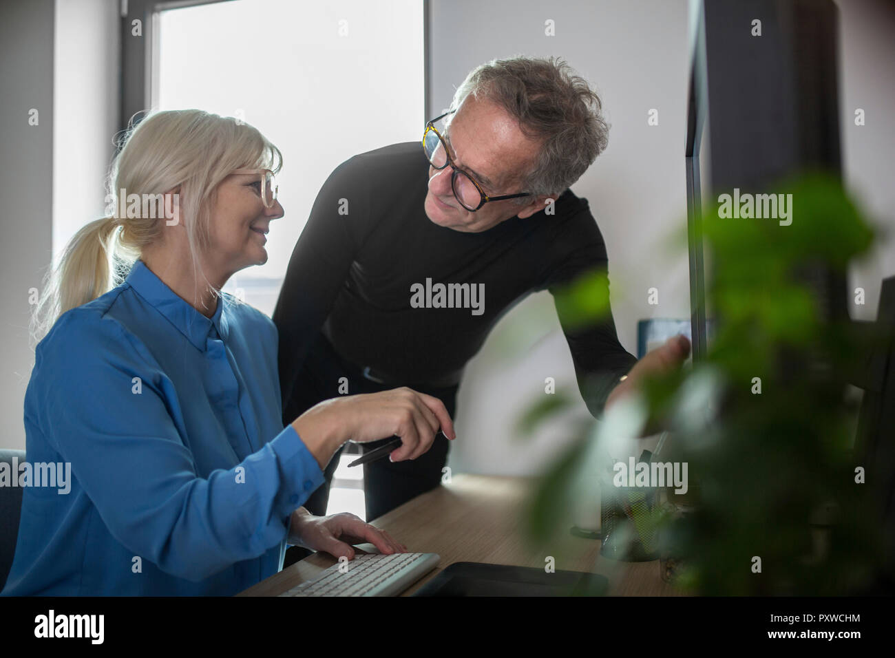 Two senior colleagues working together at desk in office Stock Photo ...