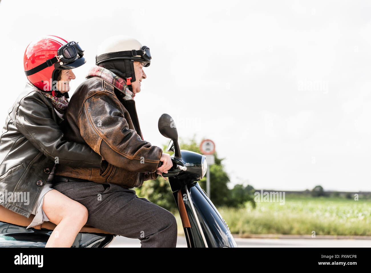 Happy senior couple riding motor scooter Stock Photo - Alamy