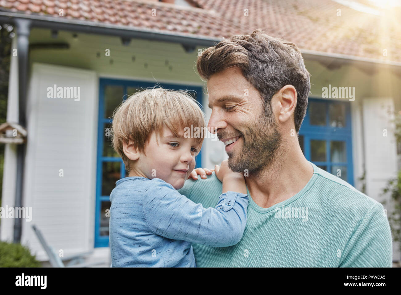 Happy father carrying son in front of their home Stock Photo - Alamy