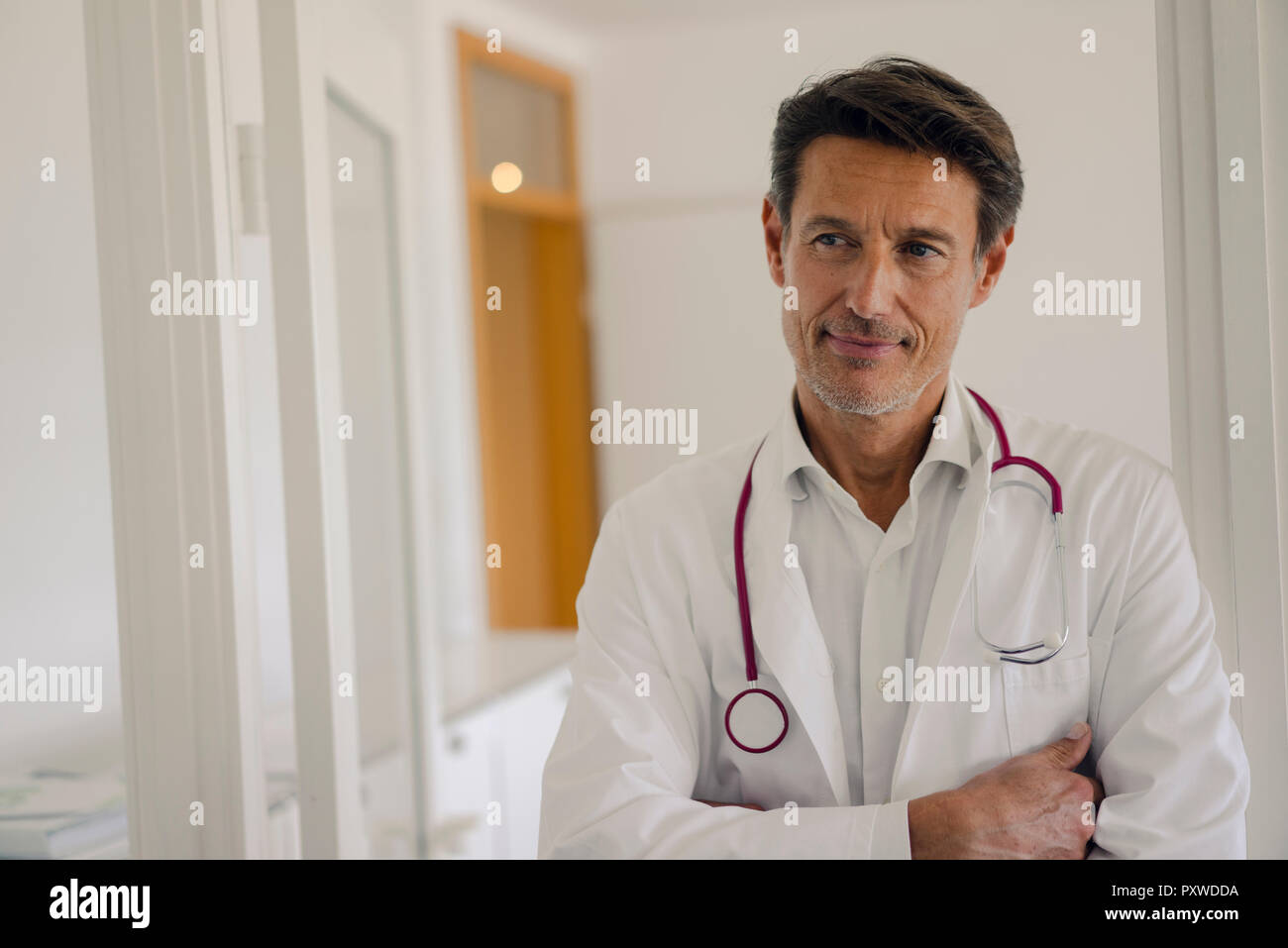 Doctor standing in hospital with arms crossed, portrait Stock Photo - Alamy