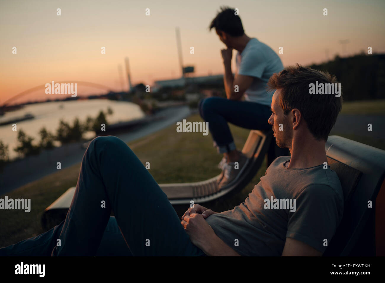 Two friends watching sunset at the river Stock Photo - Alamy