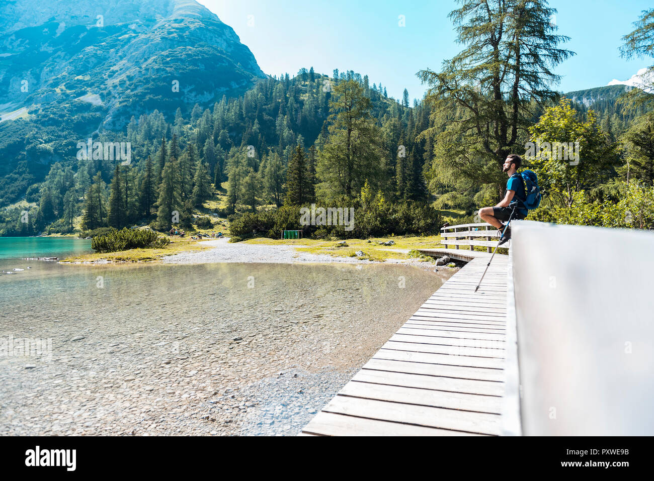 Austria, Tyrol, Hiker at Lake Seebensee sitting on boardwalk, taking a ...