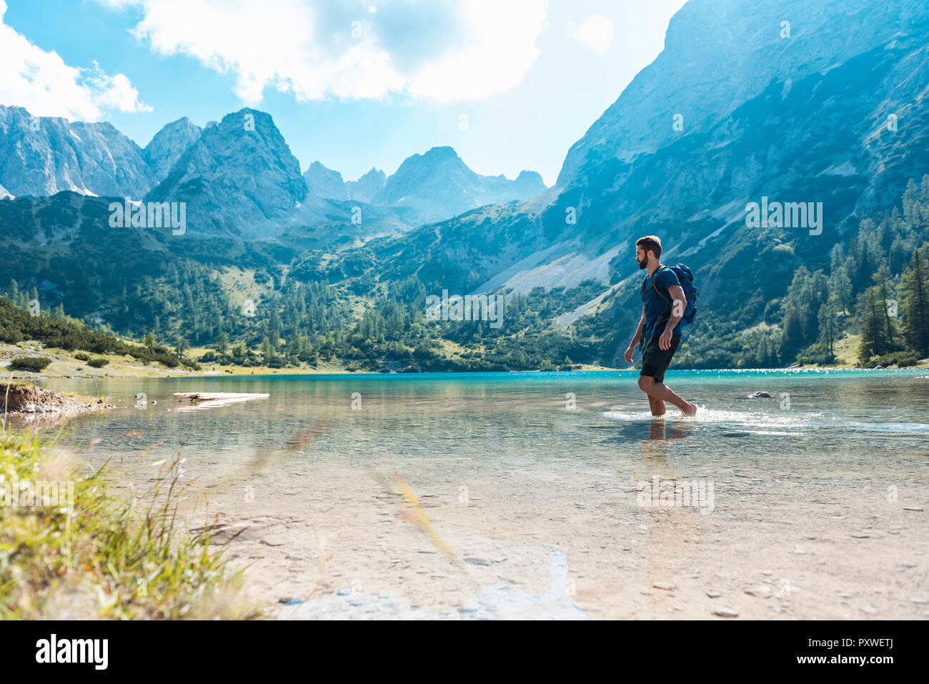Austria, Tyrol, Hiker at Lake Seebensee walking ankle deep in water ...