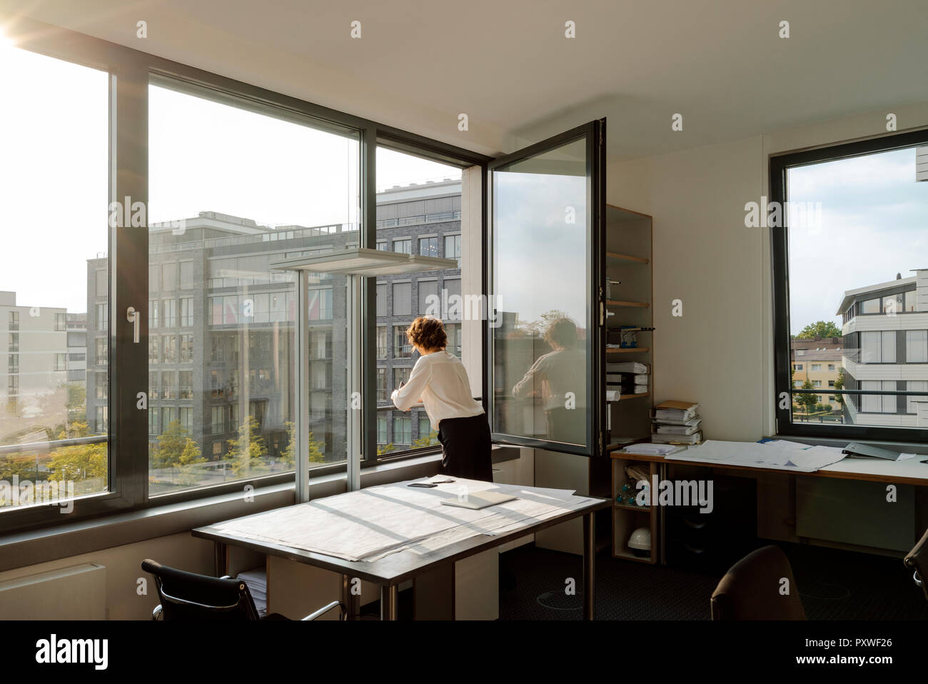 Businesswoman standing in office, looking out of window Stock Photo - Alamy
