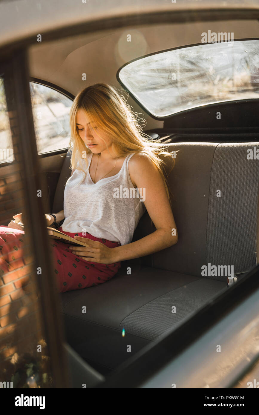 Young woman sitting in a car reading book Stock Photo - Alamy