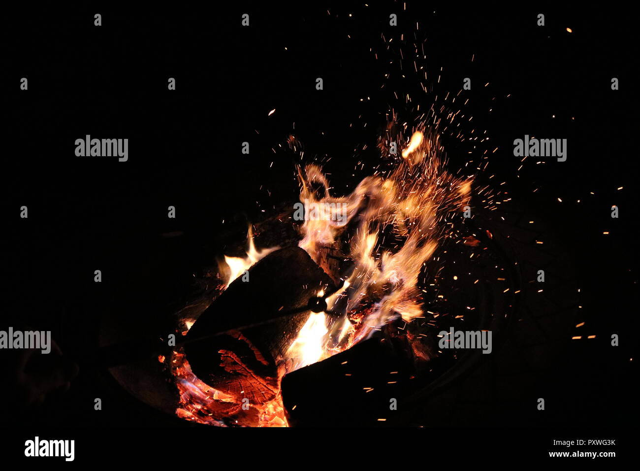 Glowing embers flying away into the night on the wind as the log in the ...