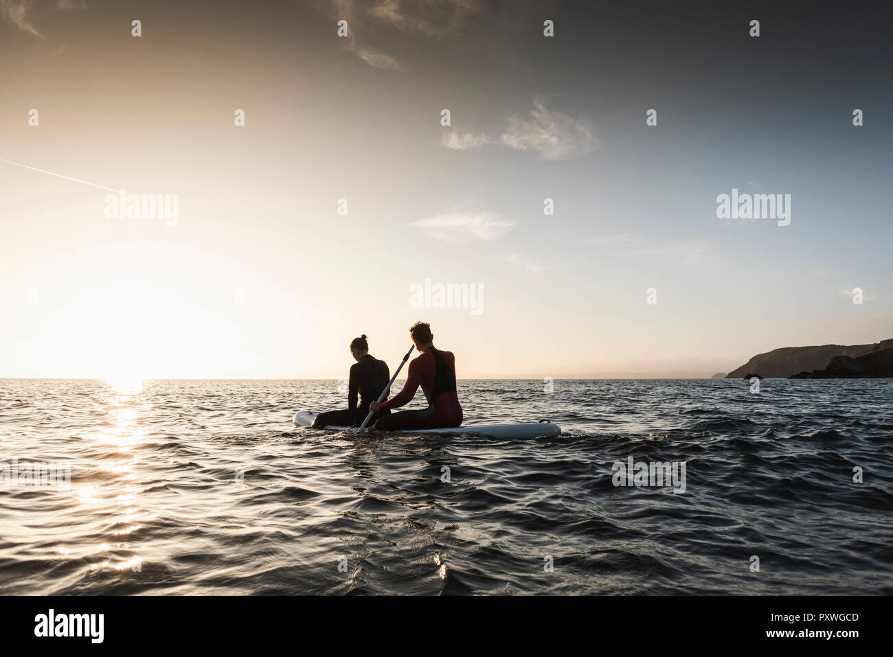 Couple on paddling on paddleboard at sunset on the sea Stock Photo - Alamy